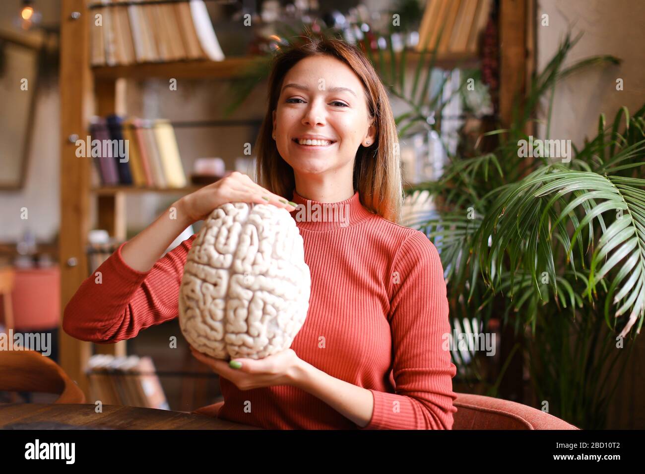 Female smiling psychologist holding human brain model at cabinet Stock ...