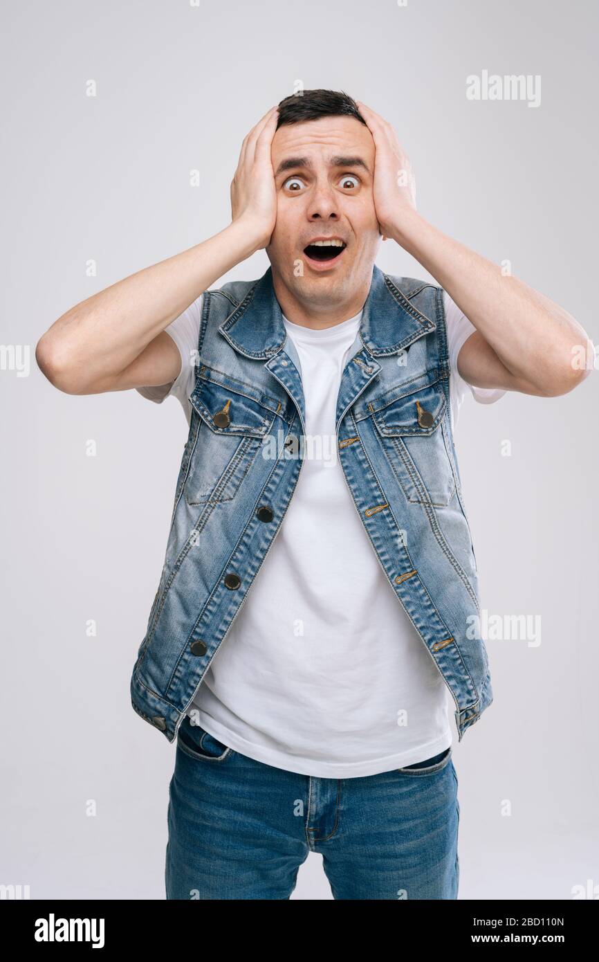 Scared young man afraid of something and looks into camera with big ...