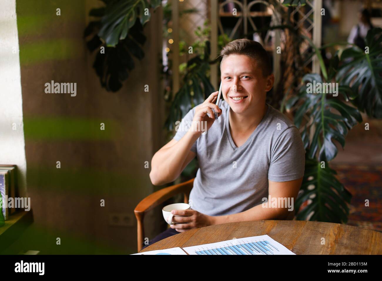 Young boy talking by smartphone and drinking coffee at cafe Stock Photo ...