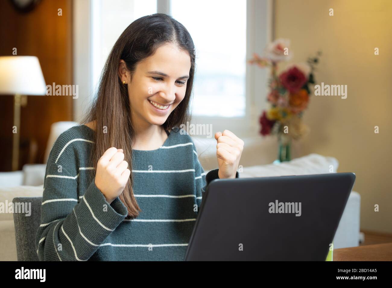 Young girl with happy expression receiving good news with her computer ...