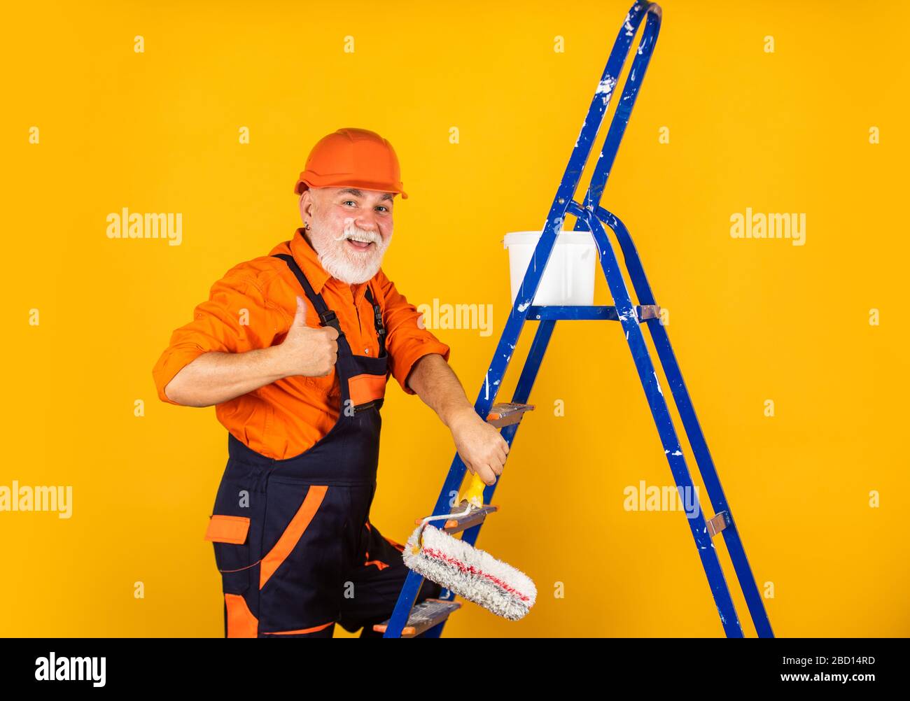 man in working clothes painting wall in empty room. painter in overall ...