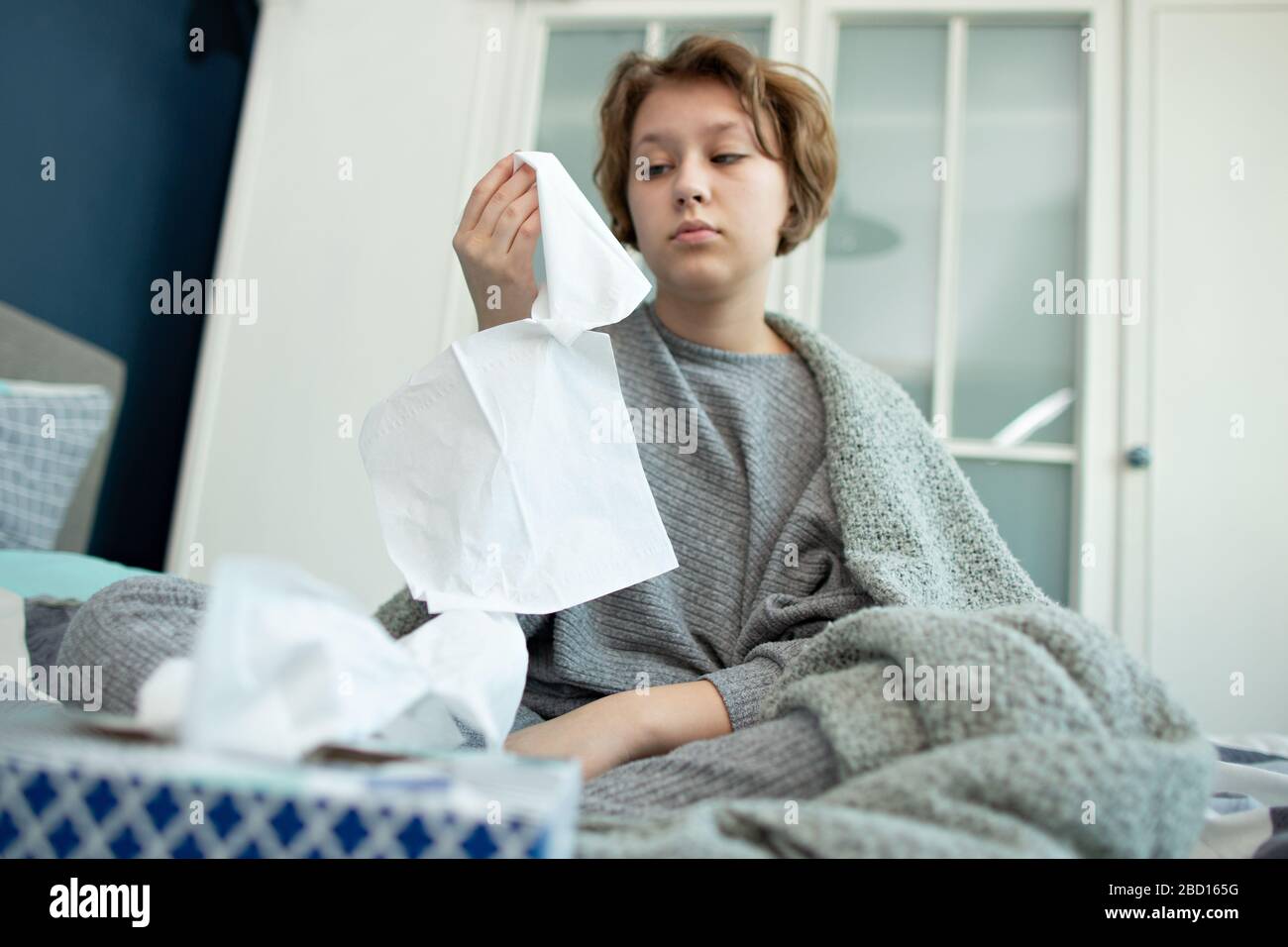 Sick girl with a thermometer Sneezing into tissue. Flu. A woman caught ...