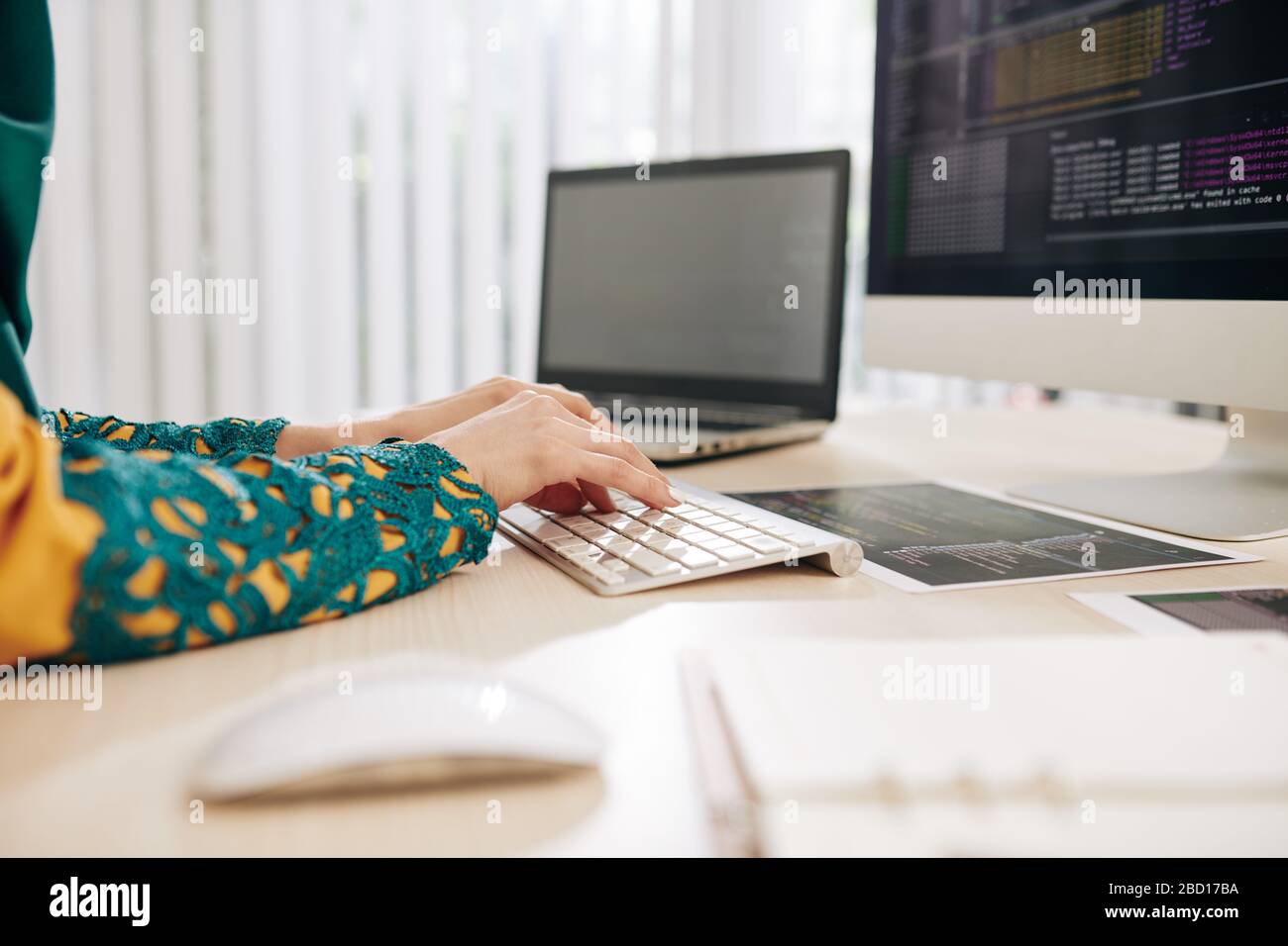 Hands of female coder sitting at her office desk and writing program ...