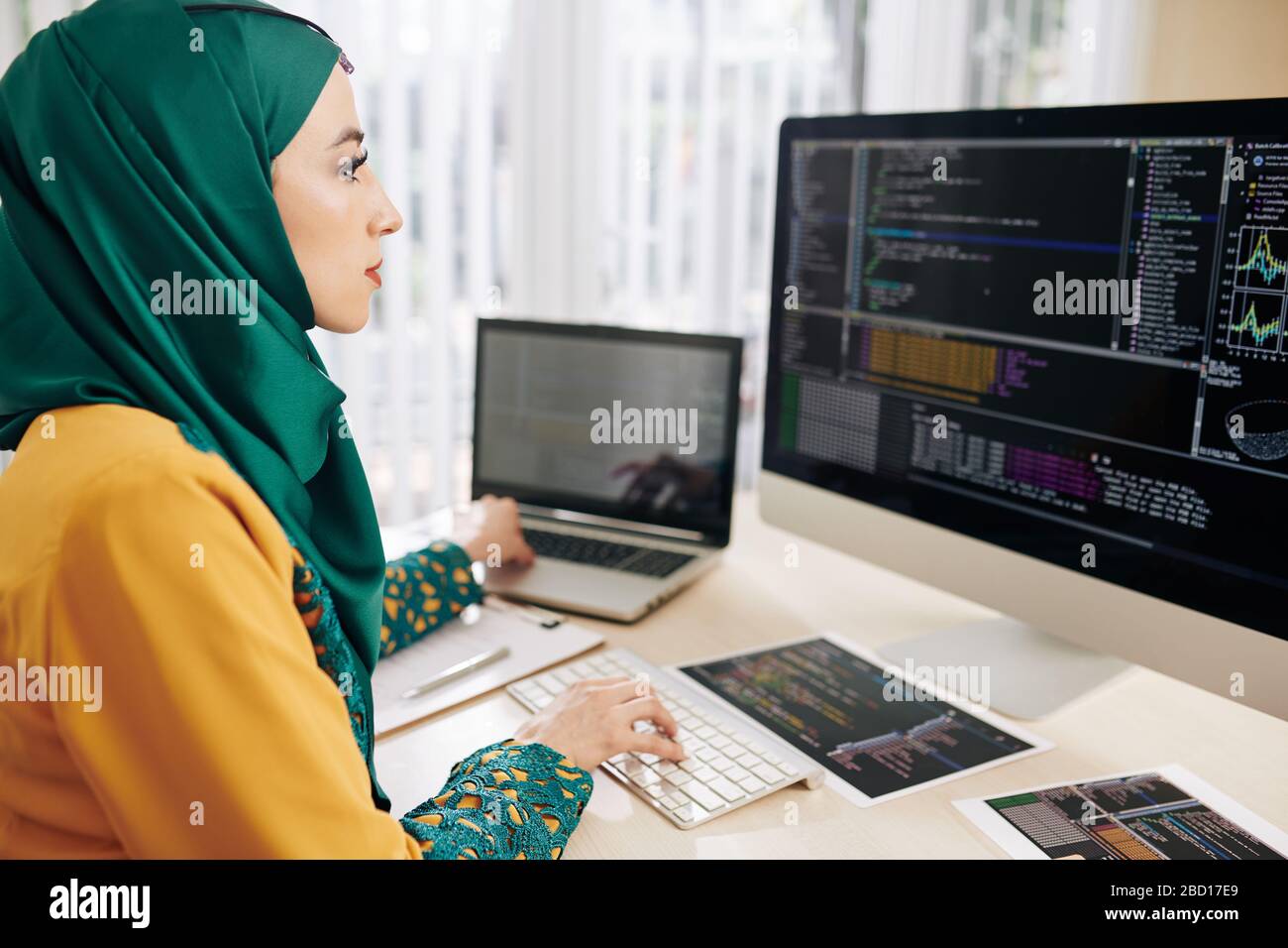 Young muslim coder using computer and laptop when testing new program ... Young muslim coder using computer and laptop when testing new program ...