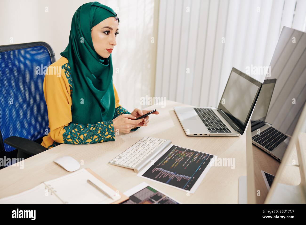 Serious pretty young muslim coder in traditional clothes reading e-mail ... Serious pretty young muslim coder in traditional clothes reading e-mail ...