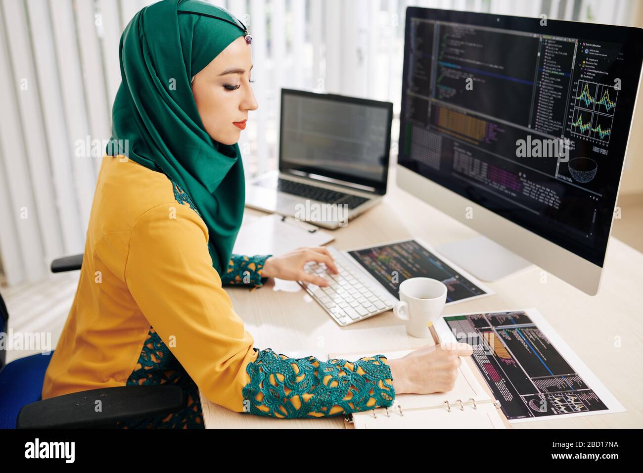 Young muslim female software developer working on programming code and ...