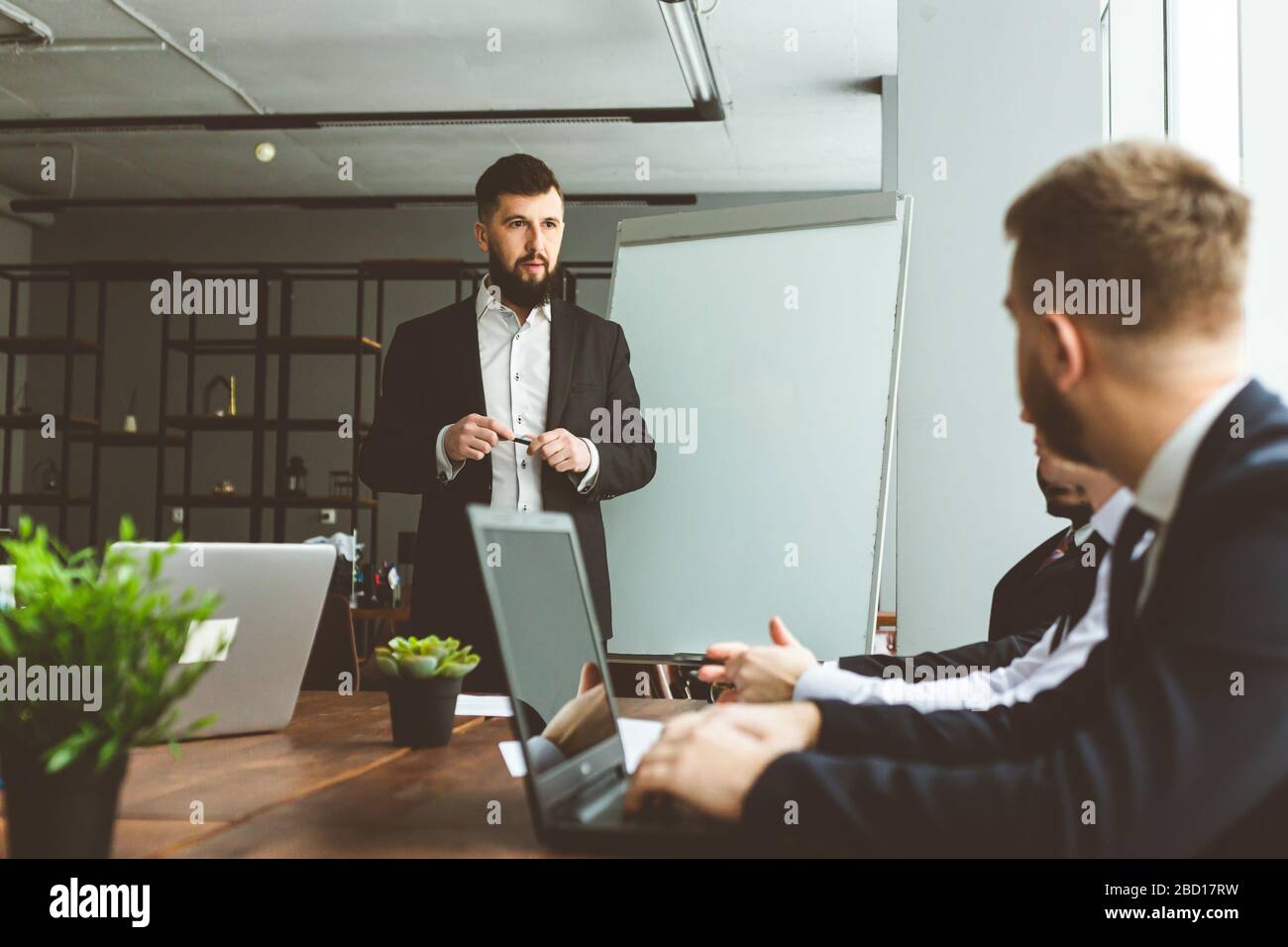 A team of young businessmen in suits working and communicating together ...