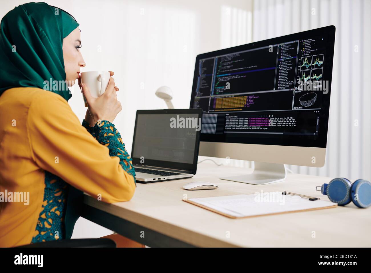 Pensive female muslim coder drinking tea and looking at programming ... Pensive female muslim coder drinking tea and looking at programming ...