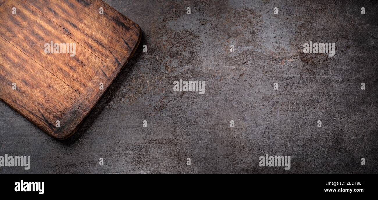 Dark metalic surface with a rectangular empty wooden cutting board in ...