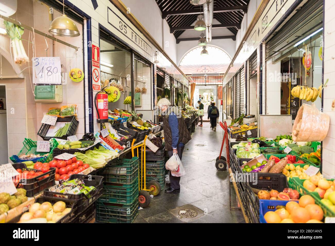 A customer looking at the produce on a fruit and vegetable stall at the ...