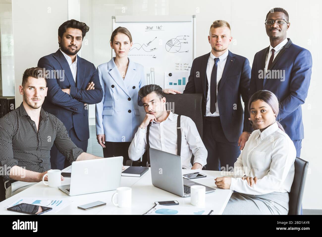 A team of young businessmen stand shoulder to shoulder, working and ...