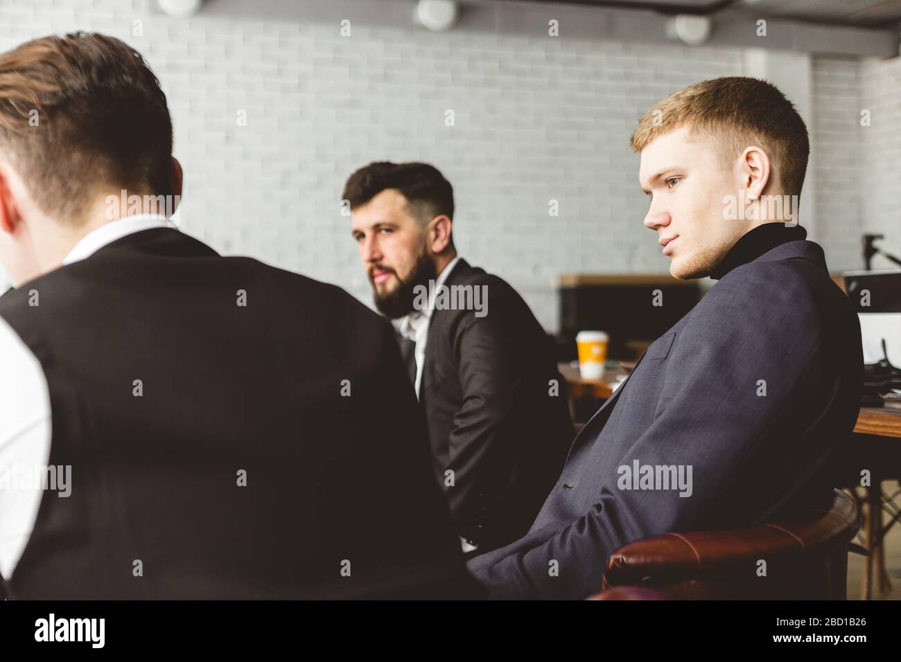 A team of young businessmen in suits working and communicating together ...