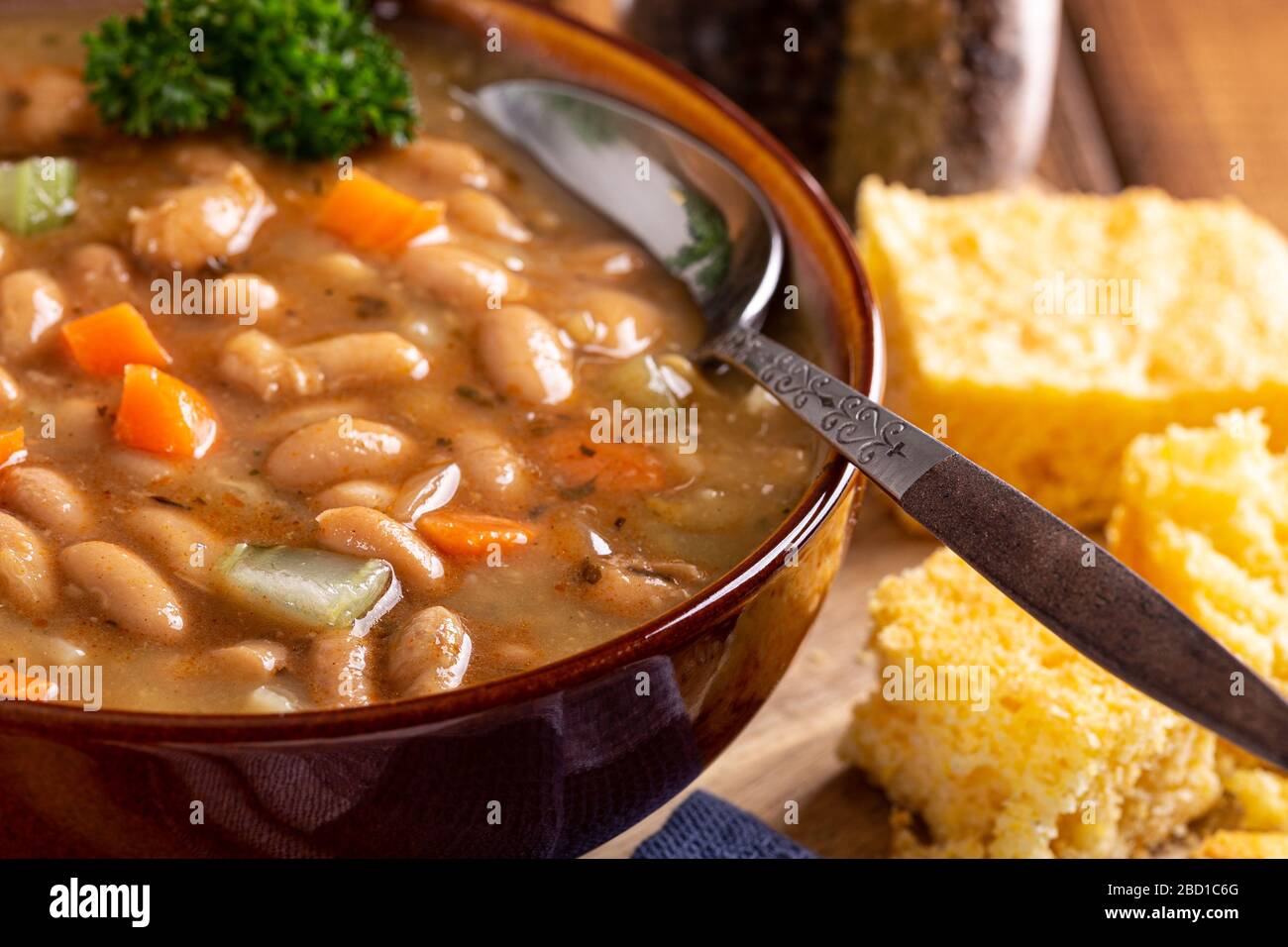 Closeup of a bowl of tasty bean soup with cornbread on a wooden table ...