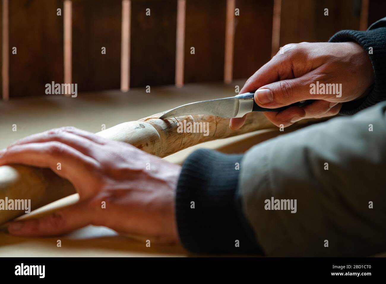Process of man making wooden walking stick indoors during quarantine ...