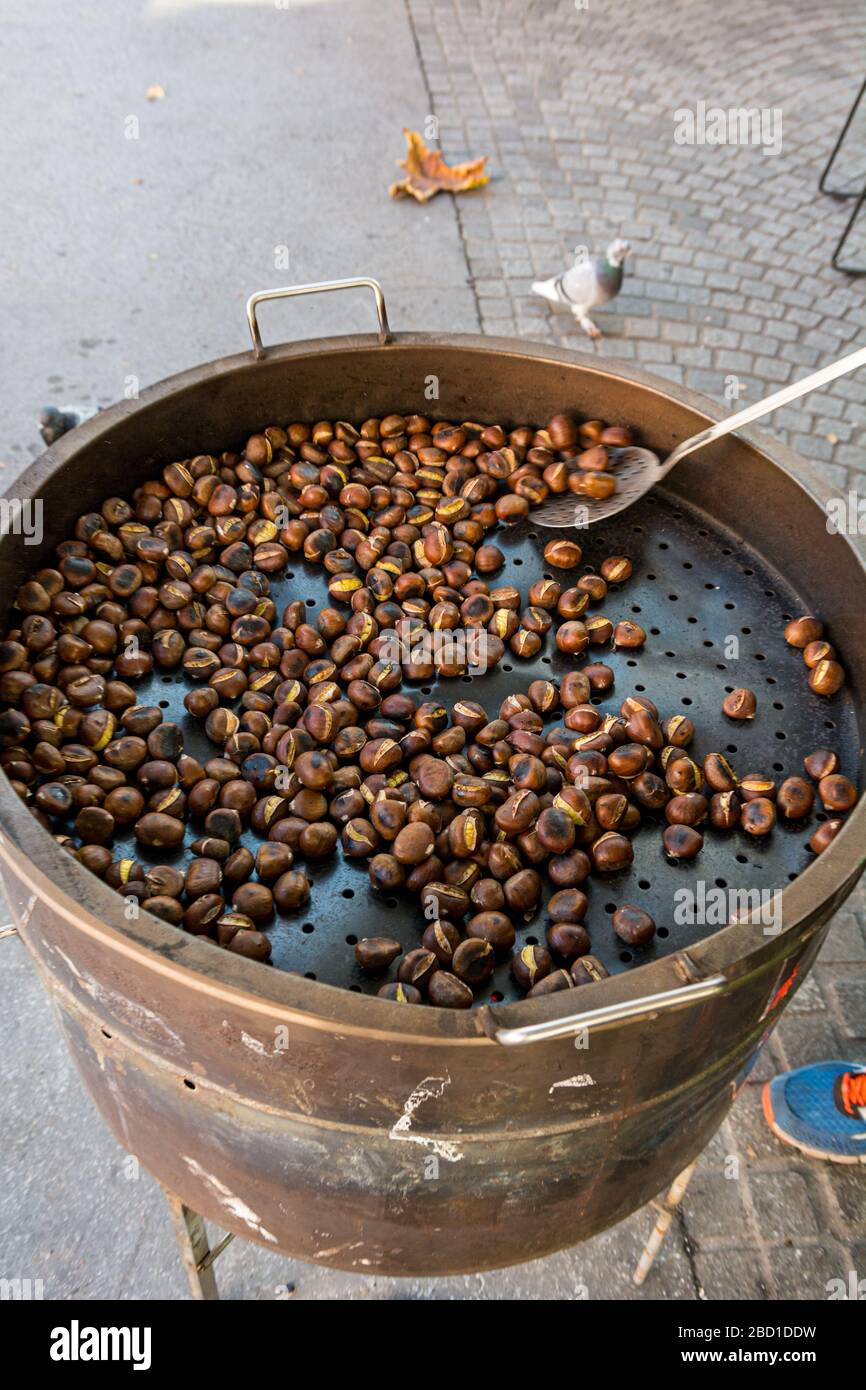 Street seller roasting delicious chestnuts on large homemade pan Stock ...