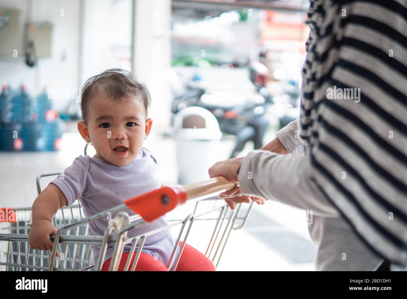 happy infant baby sitting alone in shopping cart or trolley in grocery ...
