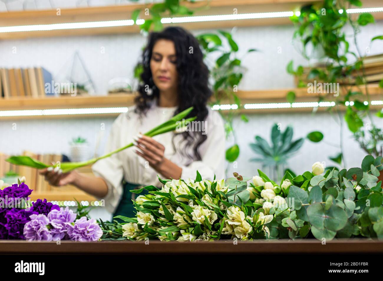 Attractive young woman florist is working in a flower shop Stock Photo ...