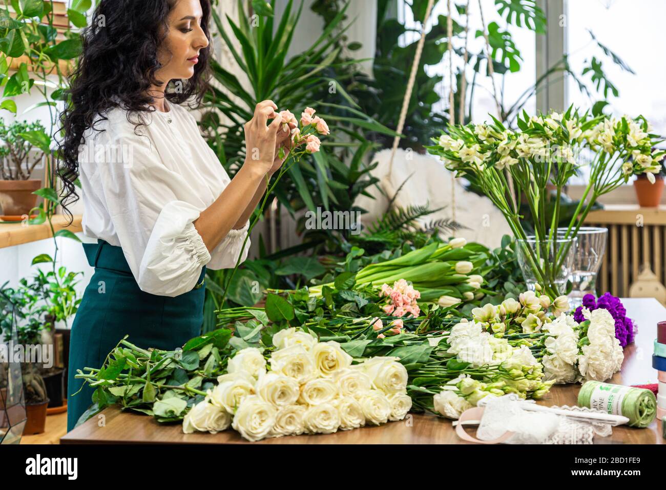 Attractive young woman florist is working in a flower shop Stock Photo ...
