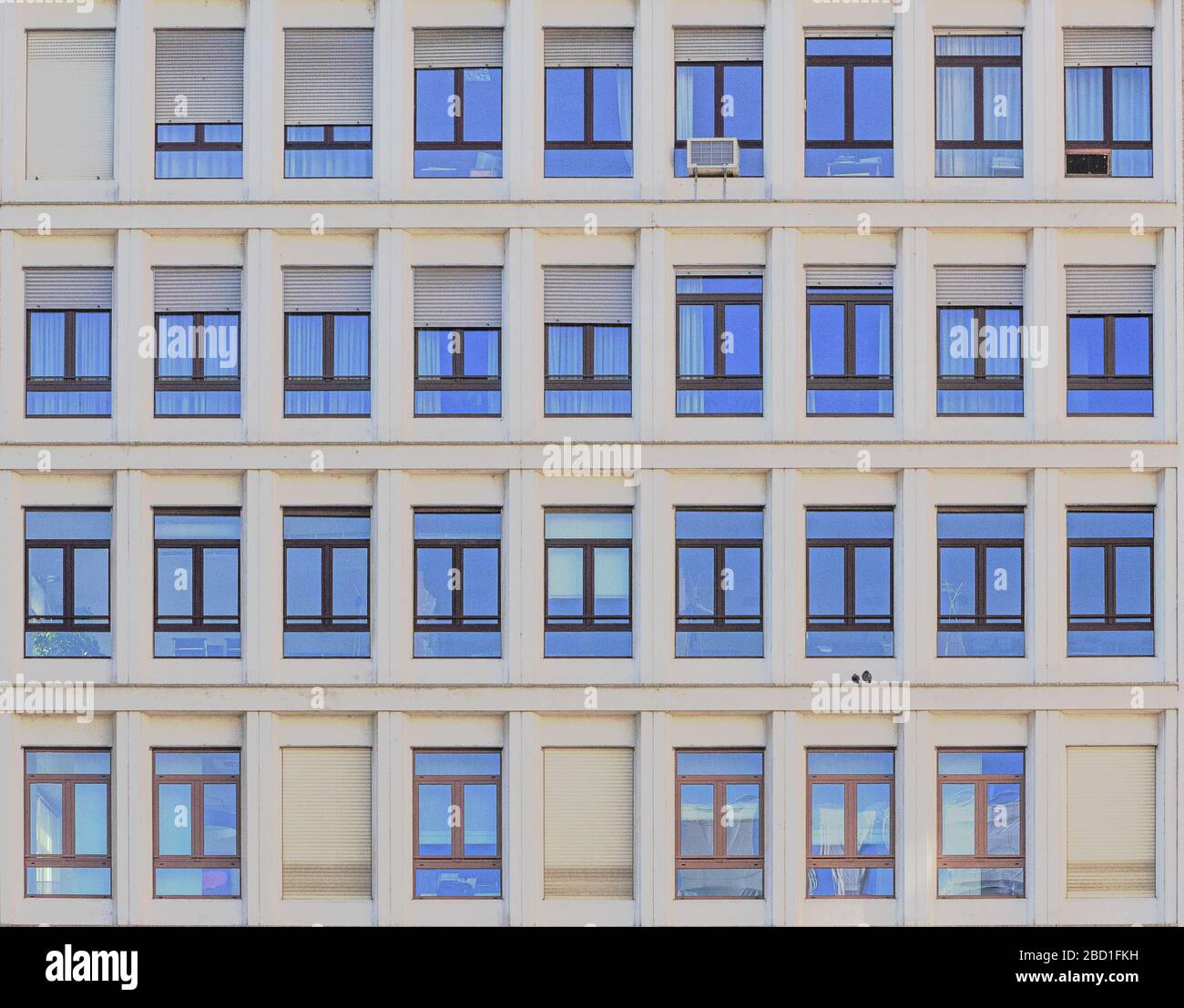symmetrical facade of a building with blue sky reflected in the grlass ...