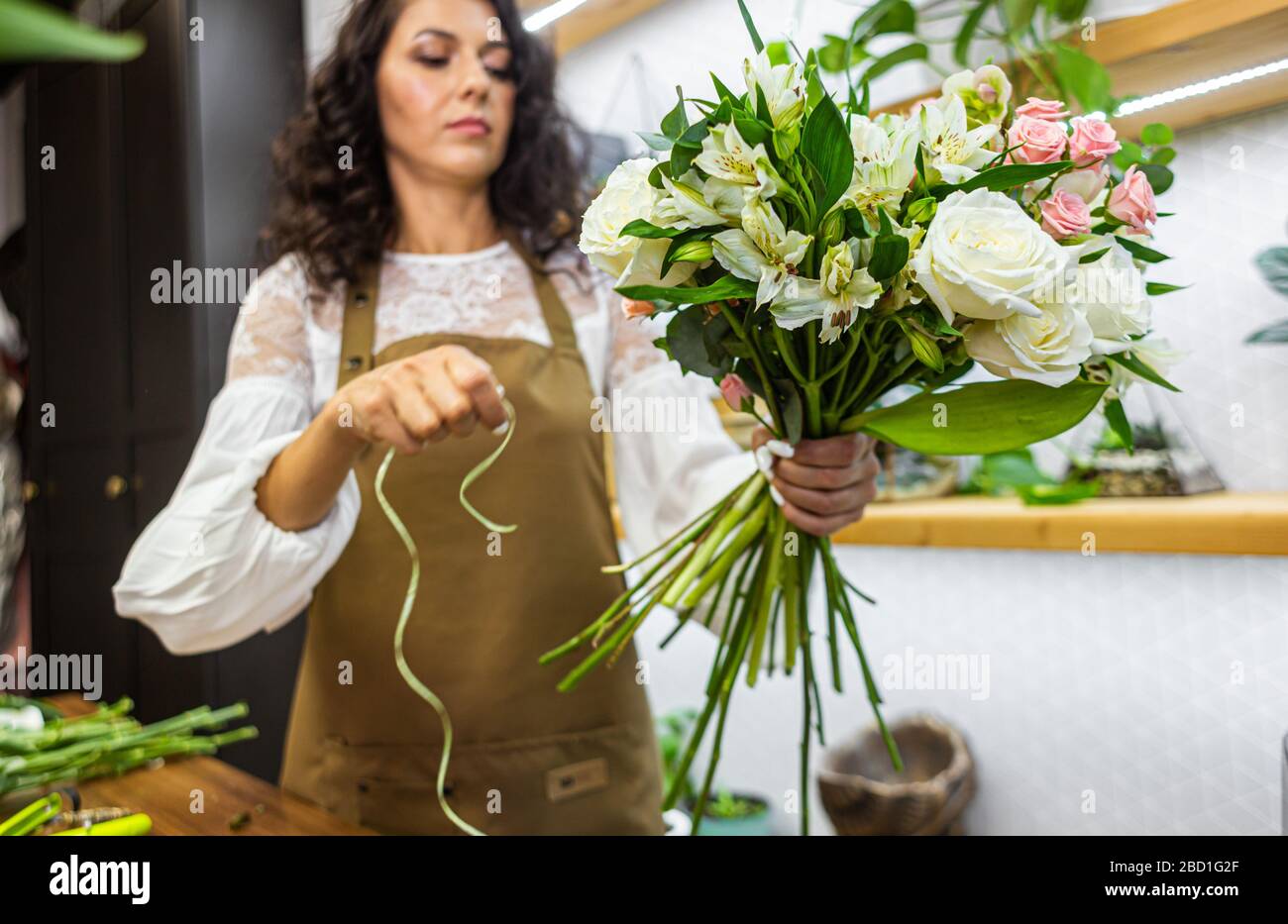 Attractive young woman florist is working in a flower shop Stock Photo ...