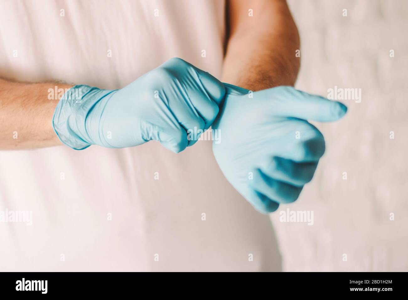 Closeup of professional doctor putting on blue latex gloves on hands ...