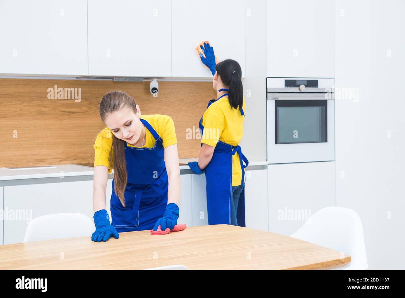 professional cleaning service. Two women in working uniform, in aprons ...