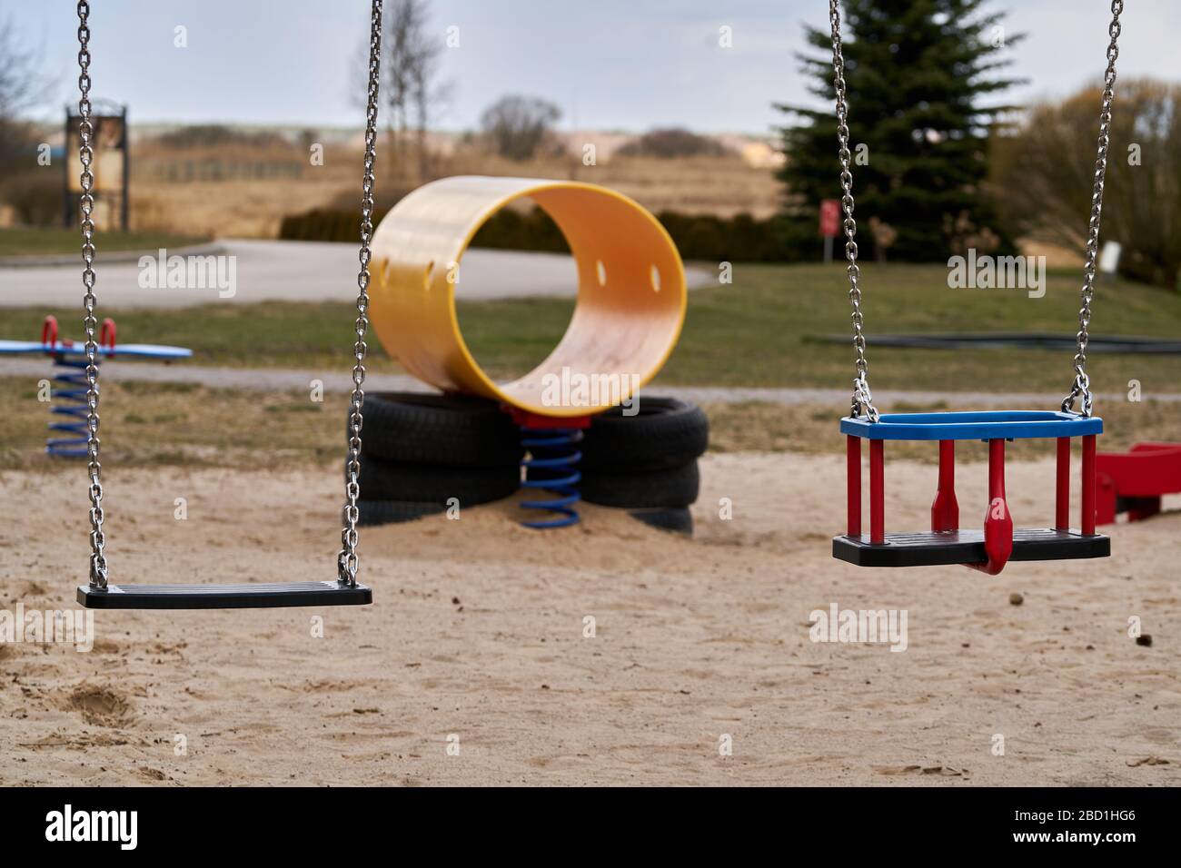 Colorful swings and rusty iron chain on cement block floor background ...