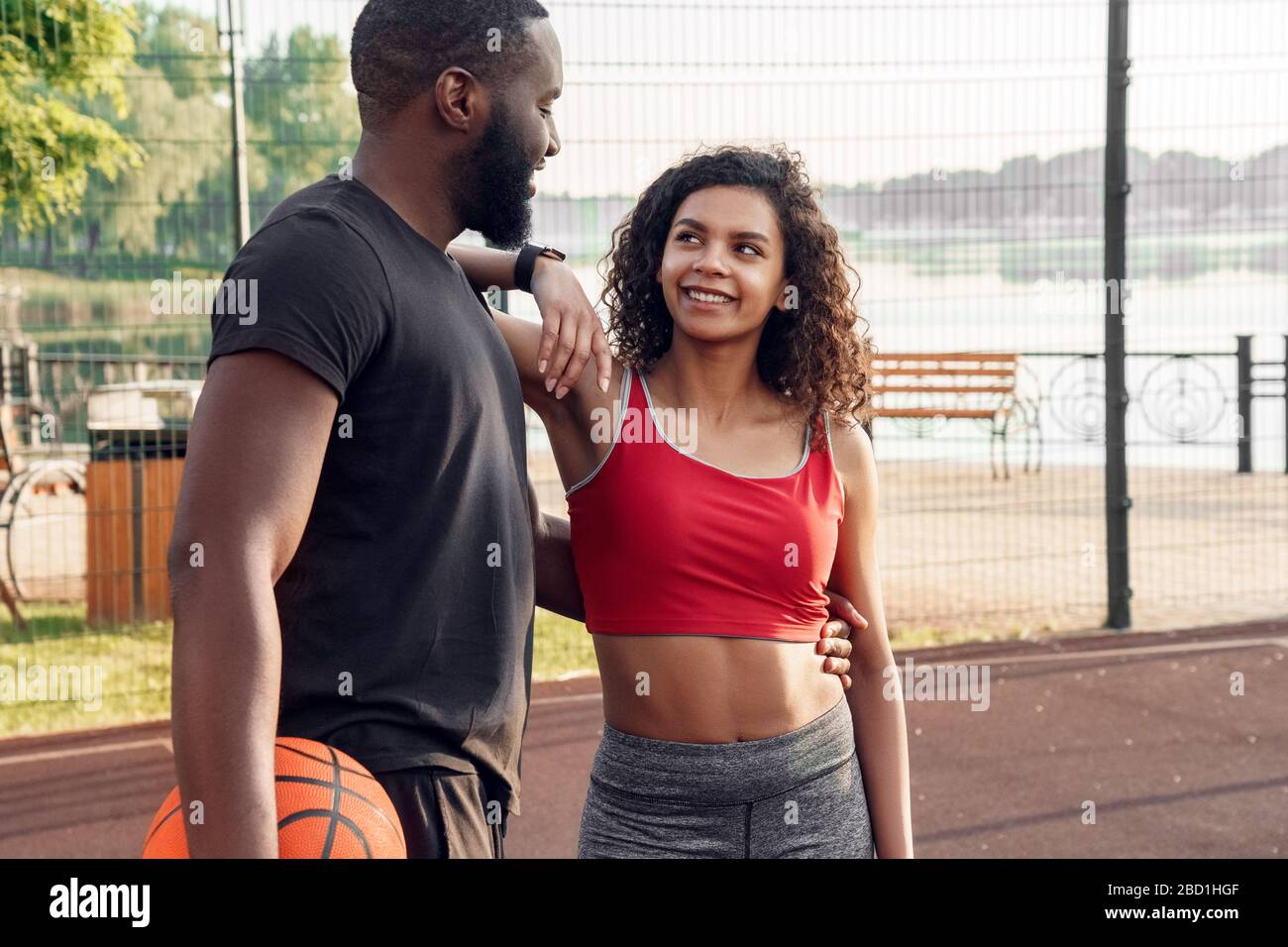 Outdoors Activity. African couple standing with ball hugging on ...