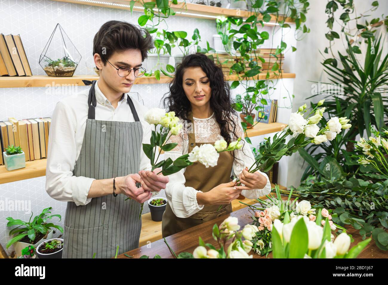Attractive experienced female florist teaches a young man how to work ...