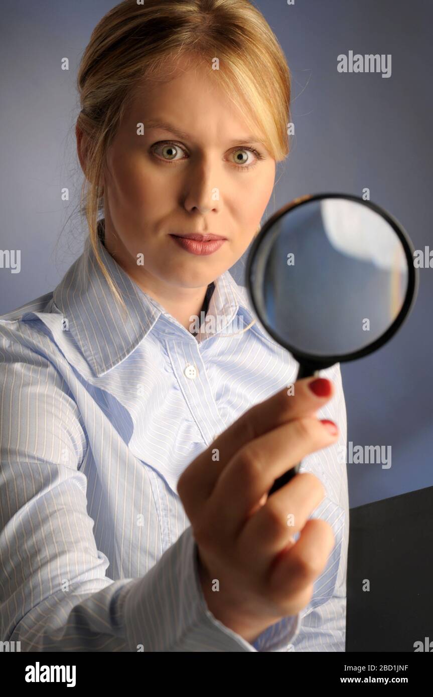 The beautiful blonde woman in blue shirt and with magnifying glass ...