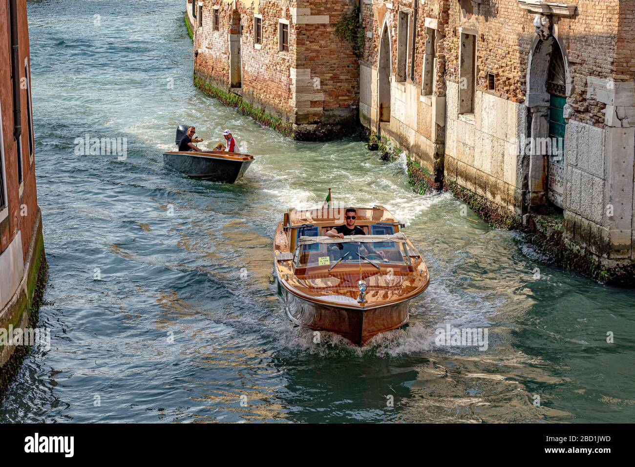 A Venice water taxi pilot steers his Water Taxi along a canal in Venice ...