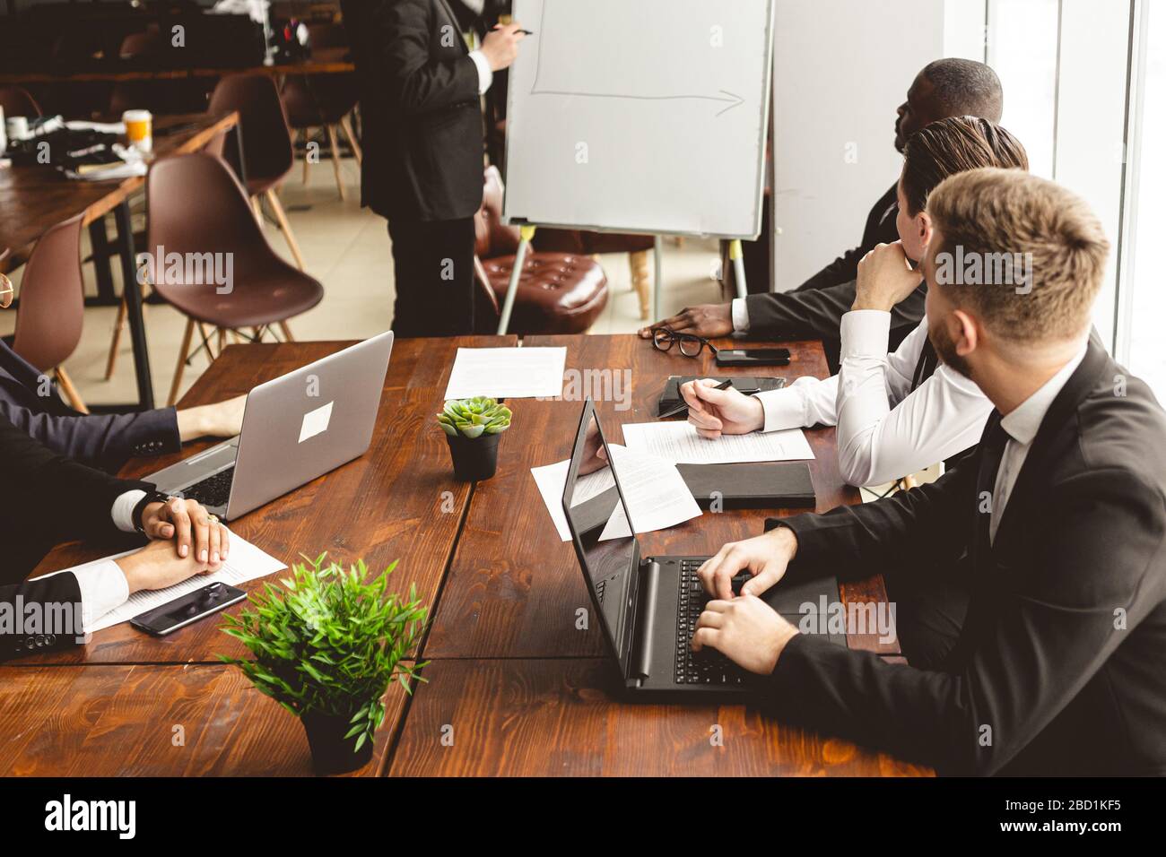 A team of young businessmen in suits working and communicating together ...