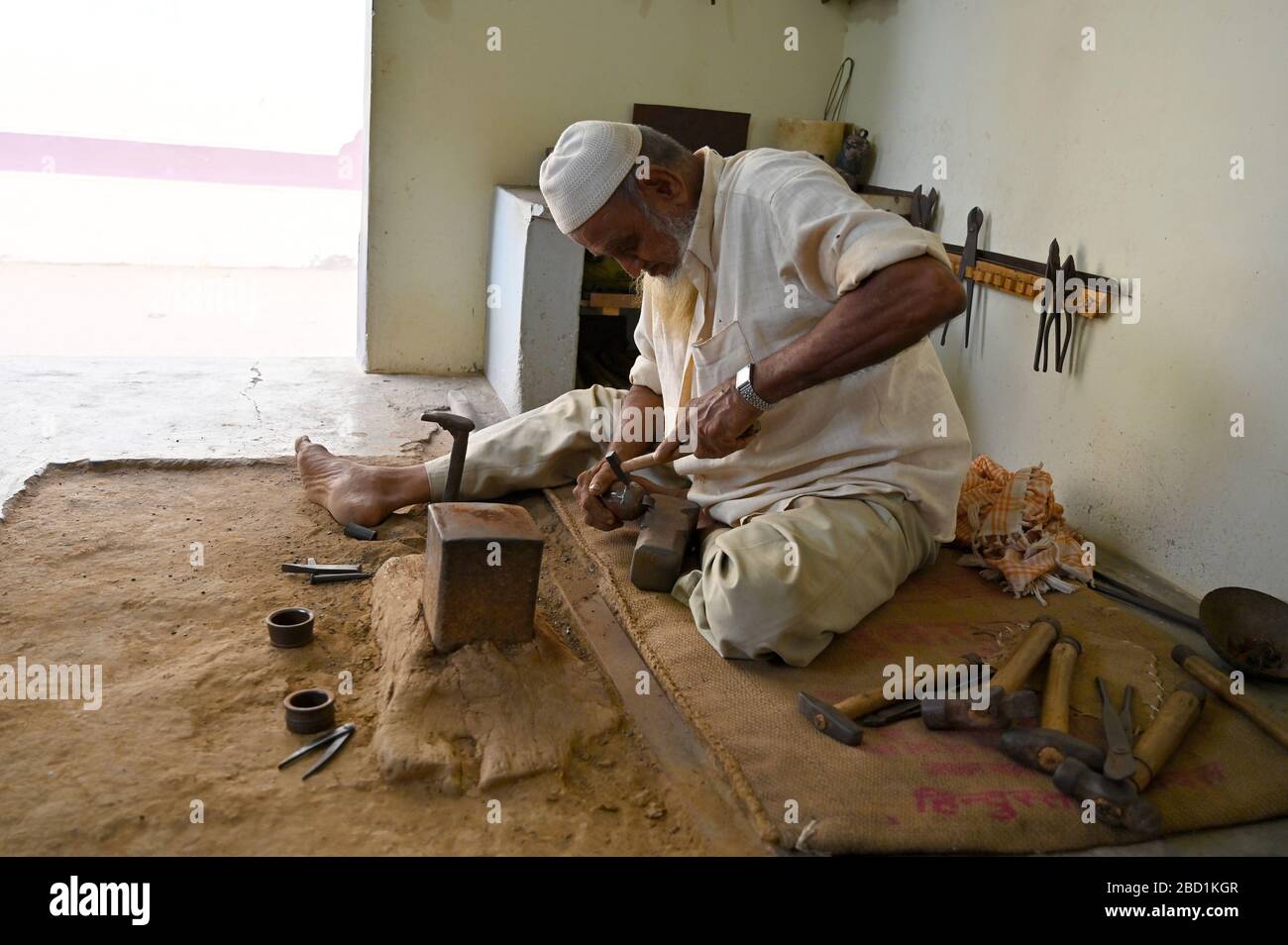Muslim bell maker beating copper into shape to make bells by hand for ...