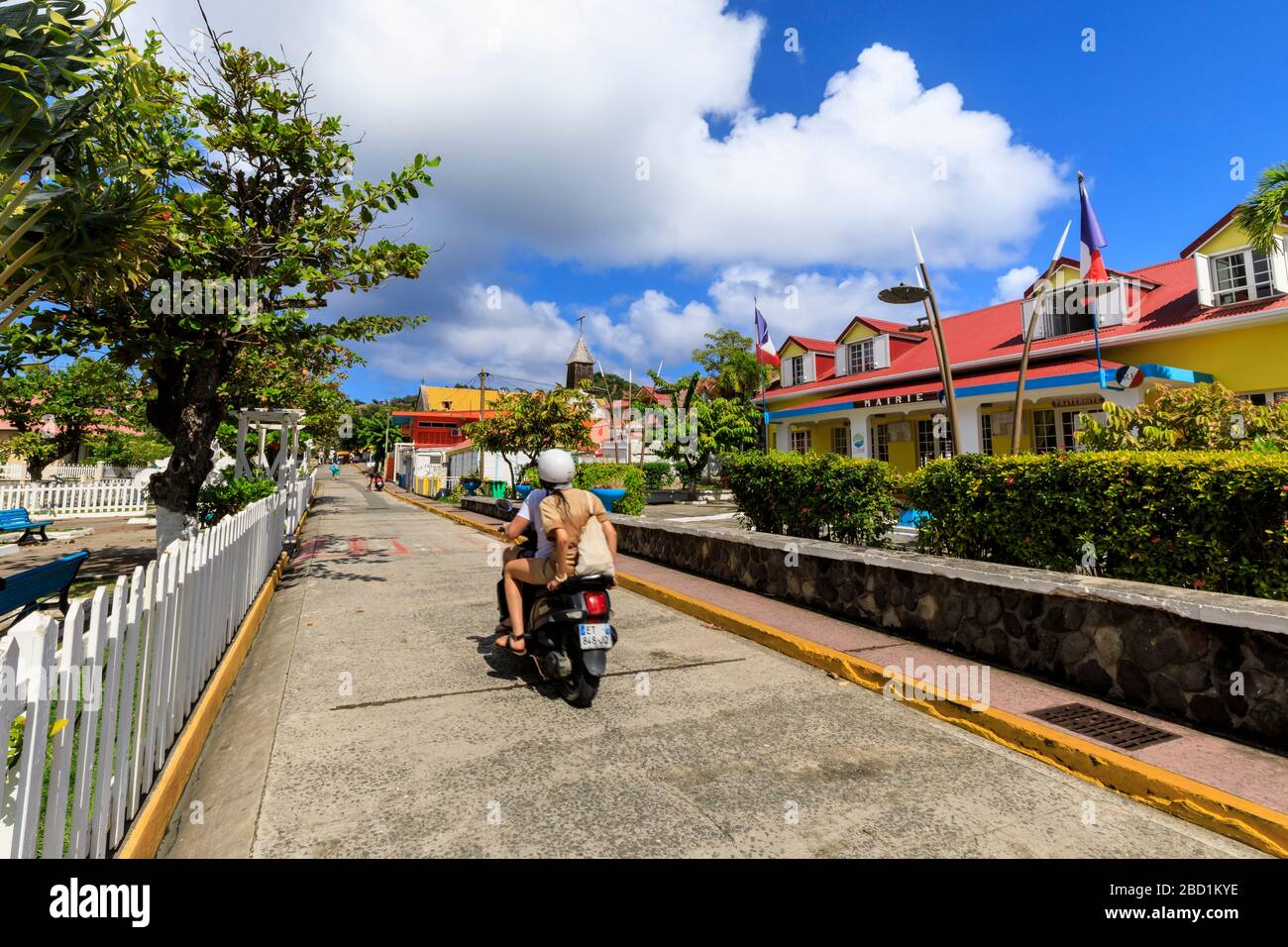 Couple on moped, colourful Bourg des Saintes town, Terre de Haut, Iles ...