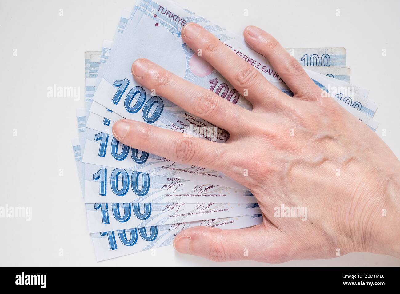 Female hand on a bunch of 100 Turkish Lira (TRY) banknotes isolated on ...