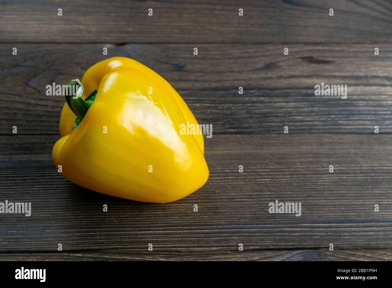 Single ripe organic fresh sweet yellow pepper on dark wooden table ...