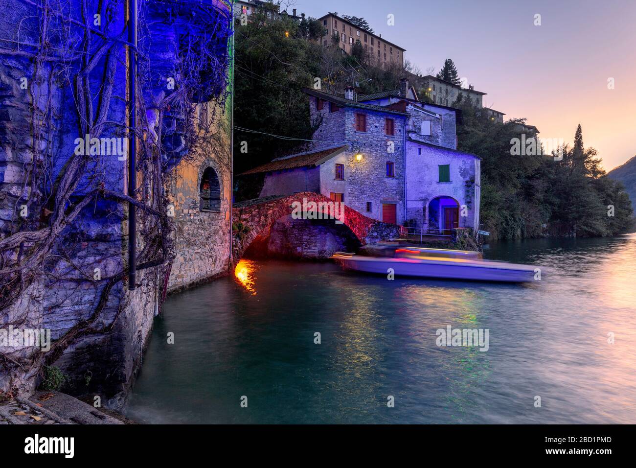 Boat in motion under the illuminated Nesso bridge, Lake Como, Lombardy ...