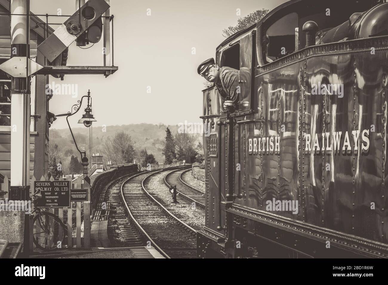 Black & white close up, UK steam train crew driver leaning looking out ...