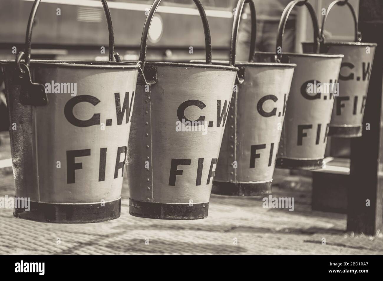 Mono close up of vintage fire buckets hanging in a row on platform of ...