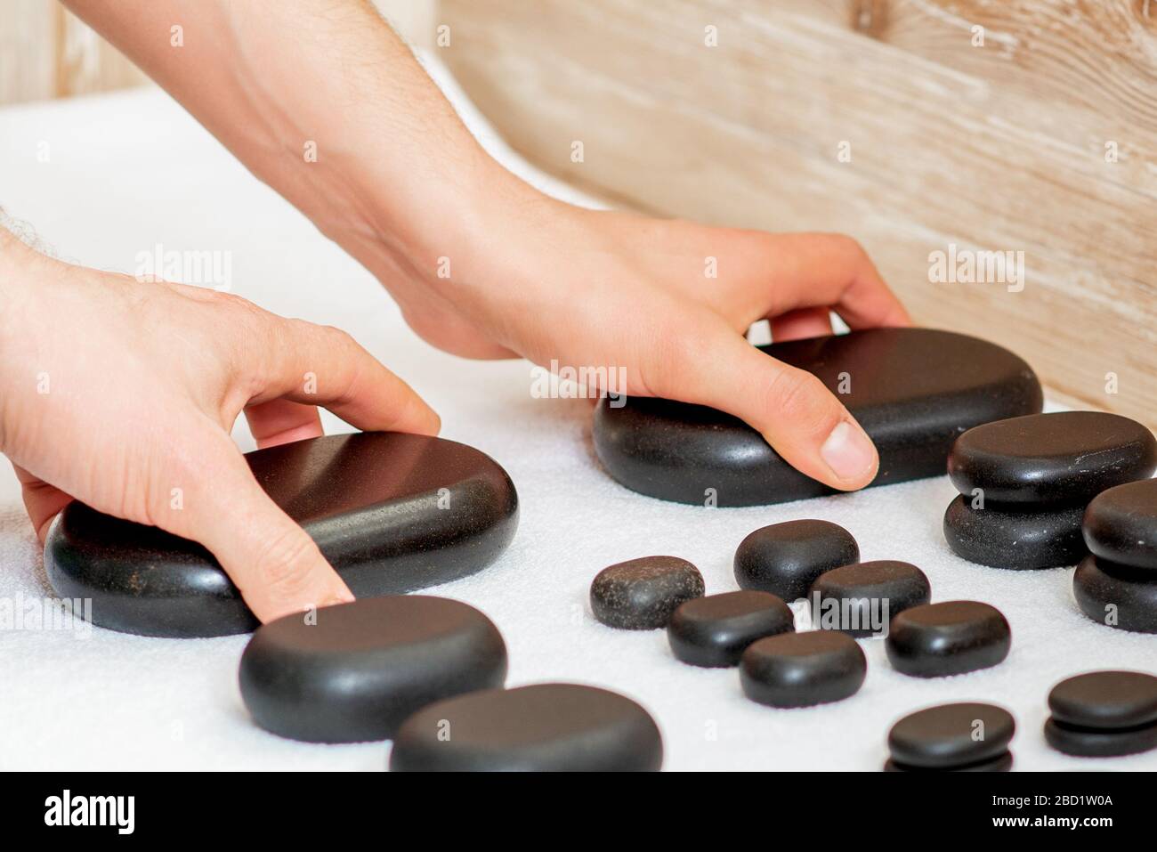 Hands taking spa hot stones from table in spa salon Stock Photo - Alamy