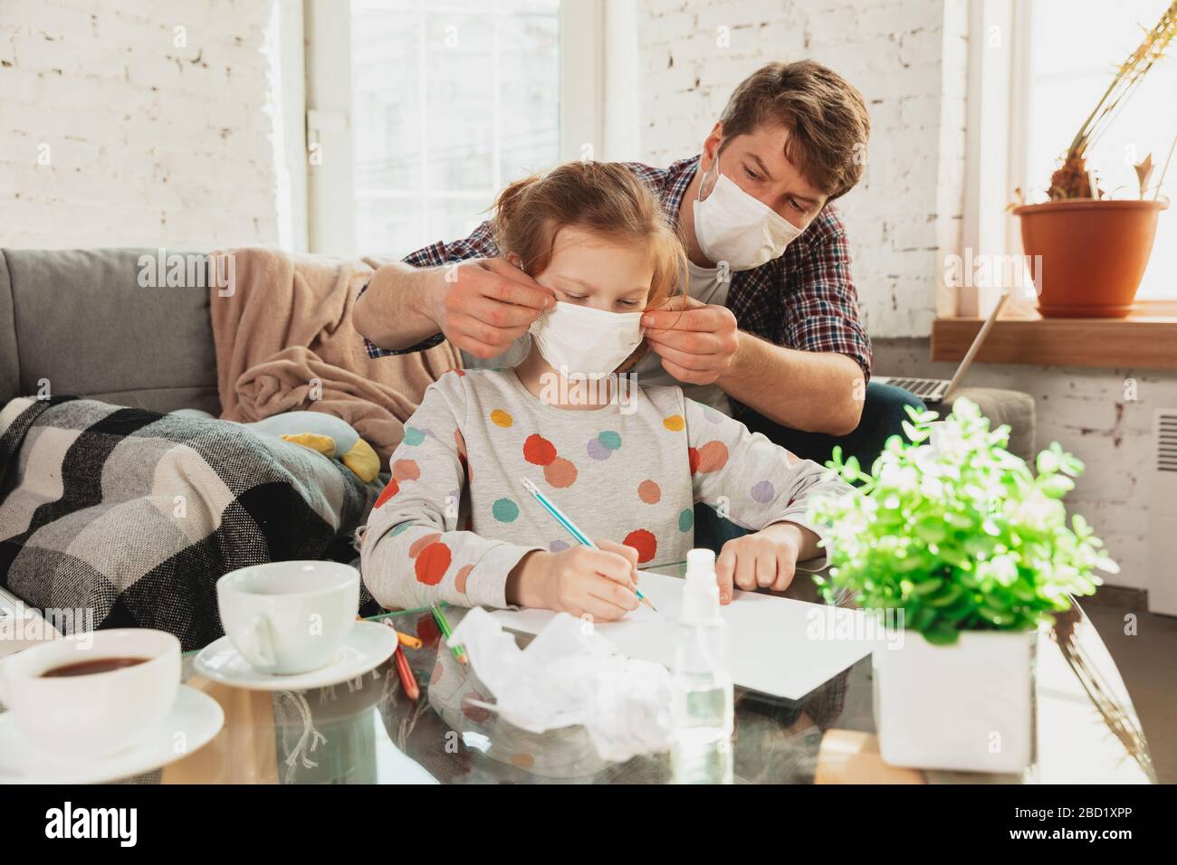 Father and daughter in face masks and gloves isolated at home with ...