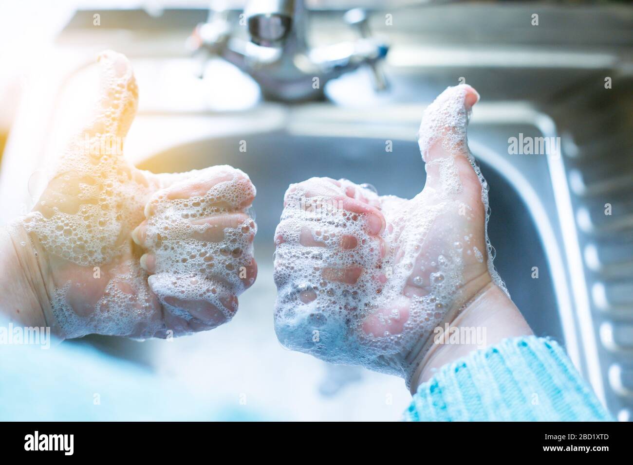 Soapy hands show like, against the background of a metal sink, in the ...