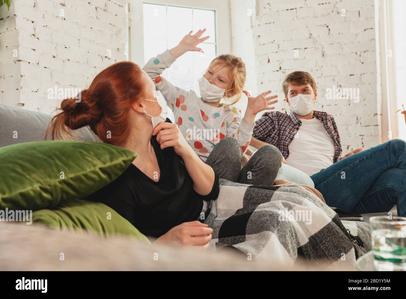 Caucasian famiy in face masks and gloves isolated at home with ...