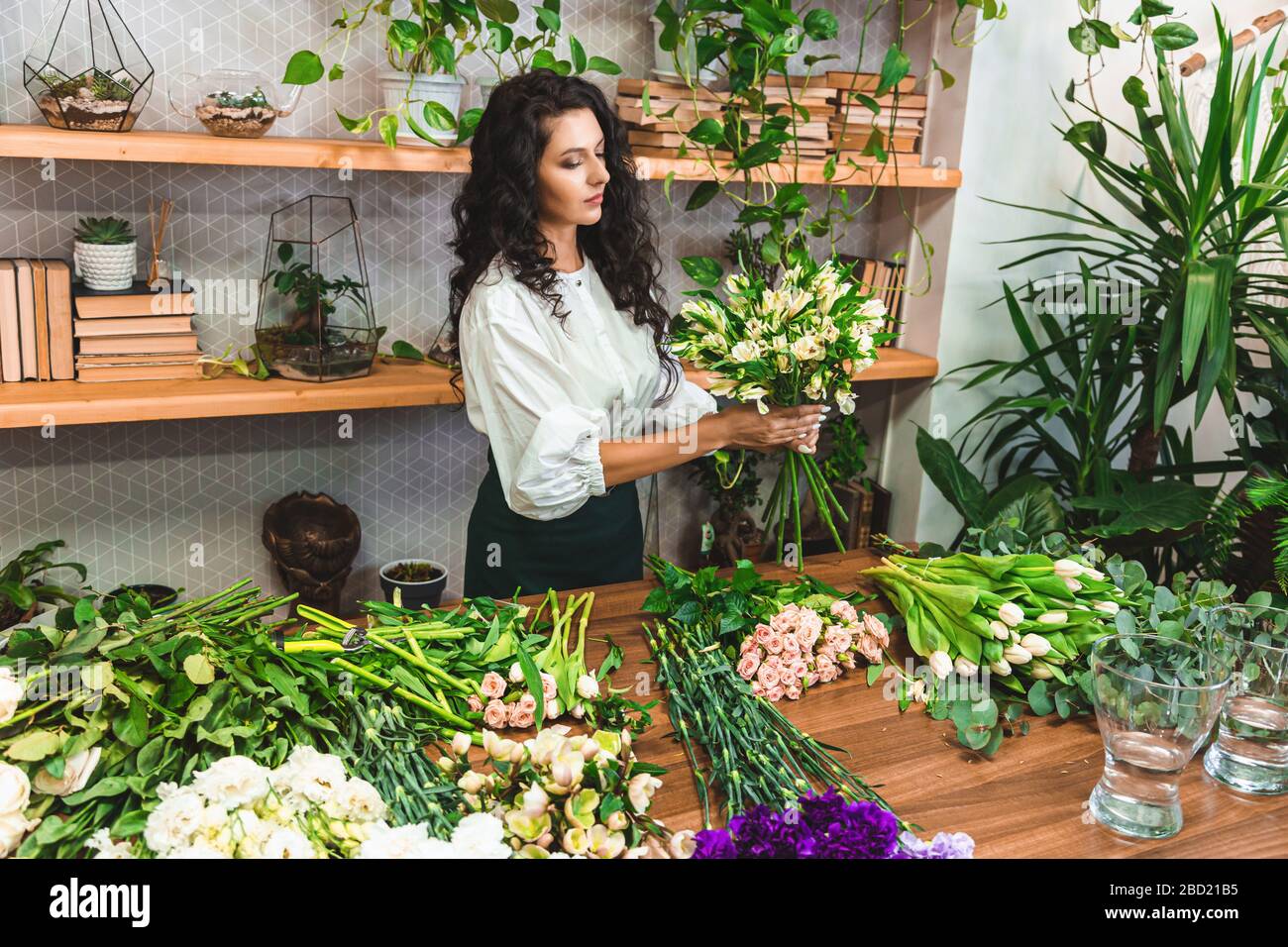 Attractive young woman florist is working in a flower shop Stock Photo ...