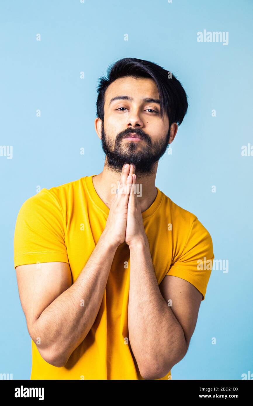 Emotional portrait of a Hindu man in a yellow T-shirt on a bright blue ...