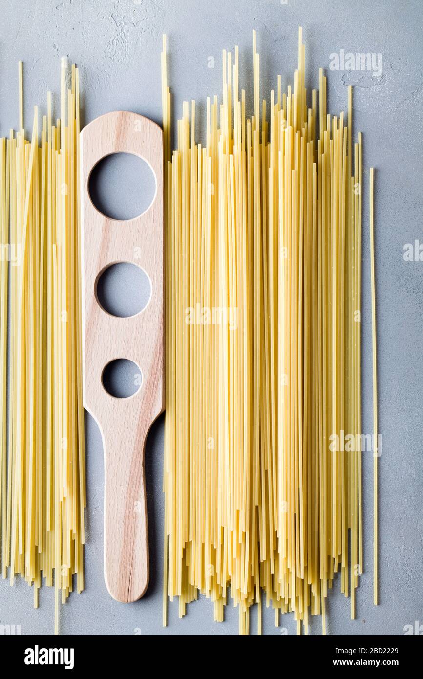 Spaghetti with spaghetti measuring stick on blue background. Close up ...