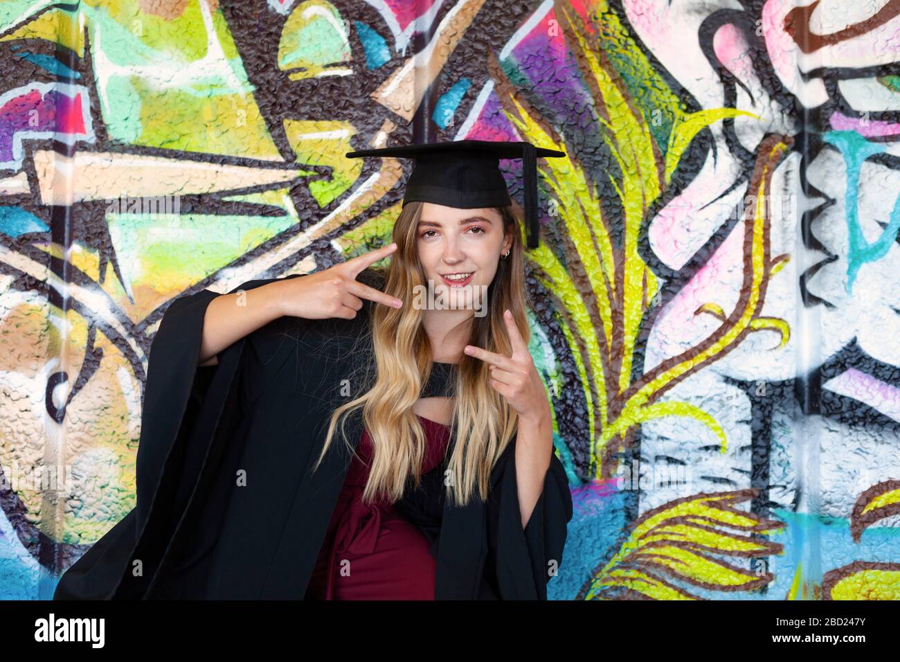 Young female graduate posing in front of graffiti Stock Photo - Alamy