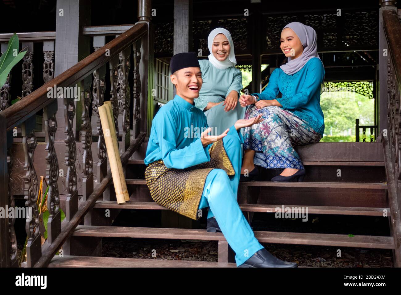 A group of three malay muslim people in traditional costume are having ...