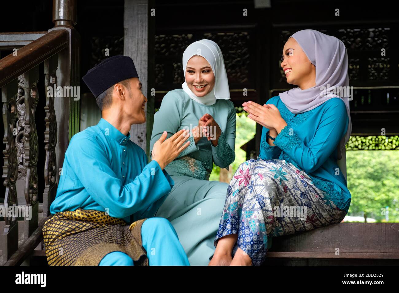 A group of three malay muslim people in traditional costume showing ...