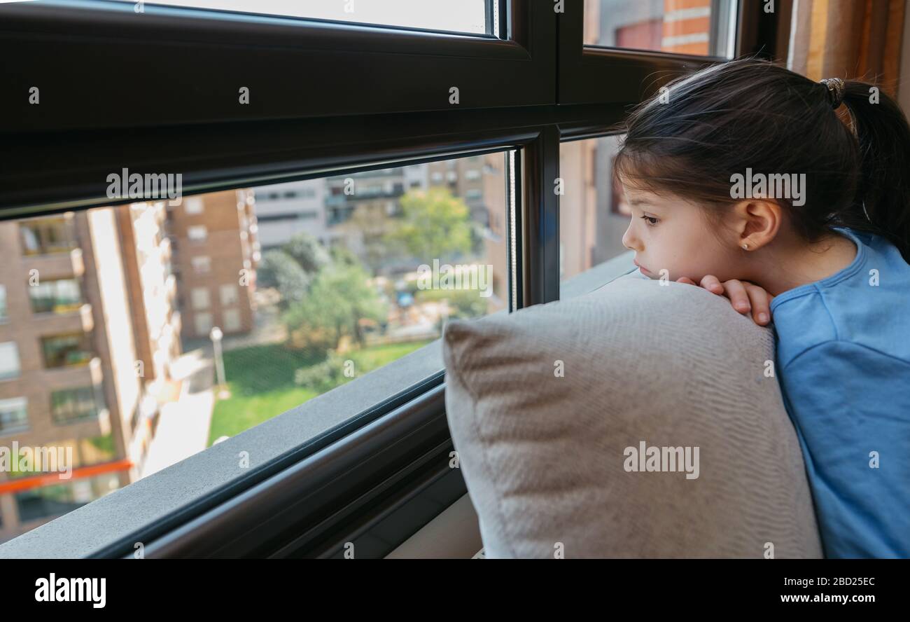 Sad girl looking out the window Stock Photo - Alamy